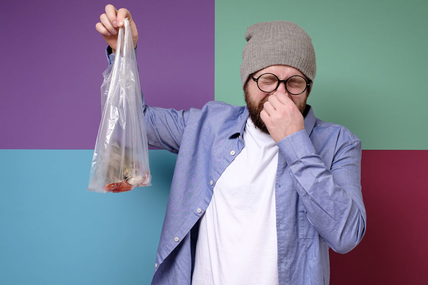 Man is holding a smelly fish in a transparent package, pinches fingers ...